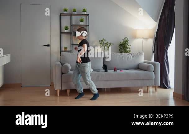 Young boy wearing VR headset actively plays immersive virtual reality ...