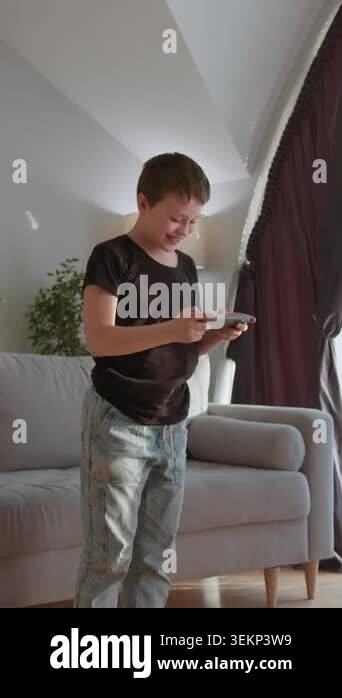 Young boy enthusiastically dances while holding smartphone, enjoying ...