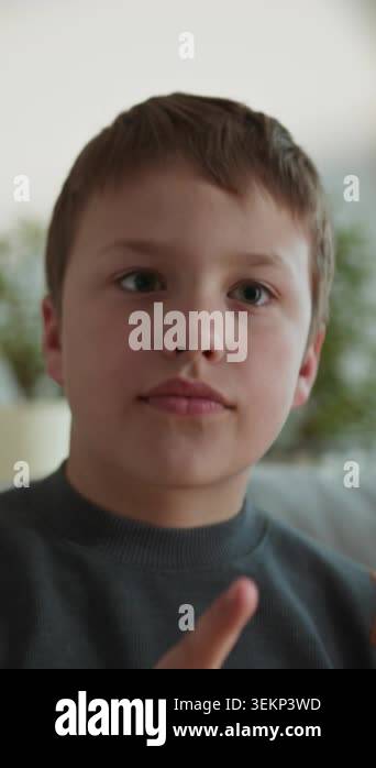 Young boy with wide eyes places finger to lips in a quiet gesture ...