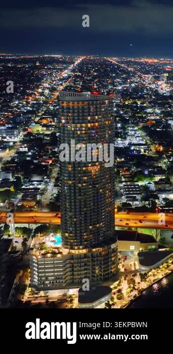 Aerial nighttime view of tall round Miami residential tower fully lit ...