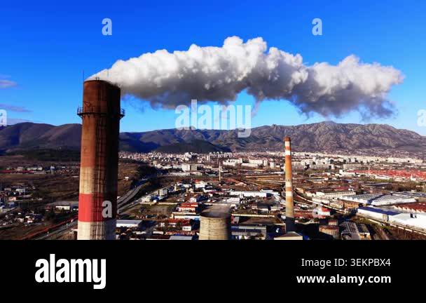 Industrial chimney emitting smoke over city with mountains, Bulgaria ...