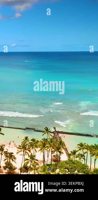 Waikiki ocean with surfers, sandy beach, stone breakwater, lifeguard ...