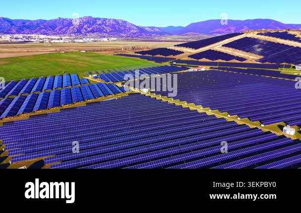 Tilted blue photovoltaic rows with green grass strips and gravel paths ...