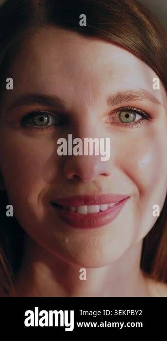 Close-up of a woman s face with green eyes and a gentle smile, showing ...