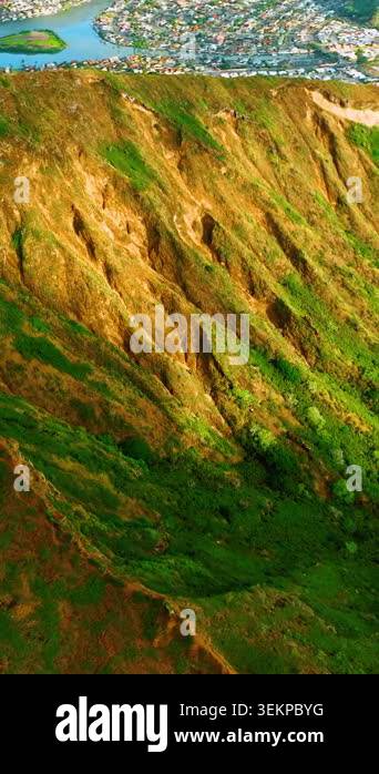 Close aerial view of deeply eroded orange-brown volcanic hillside with ...