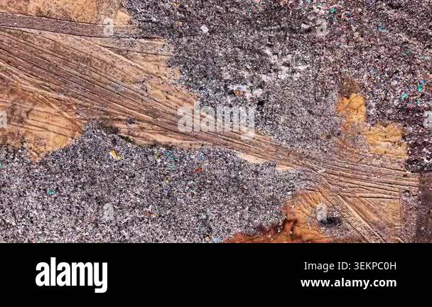 Bird's eye viewpoint of plastic debris bisected by brown soil tracks ...