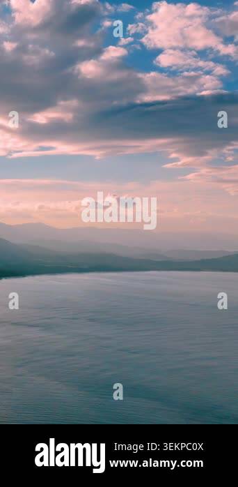 Wide seascape of calm bay with layered mountain silhouettes, pastel ...