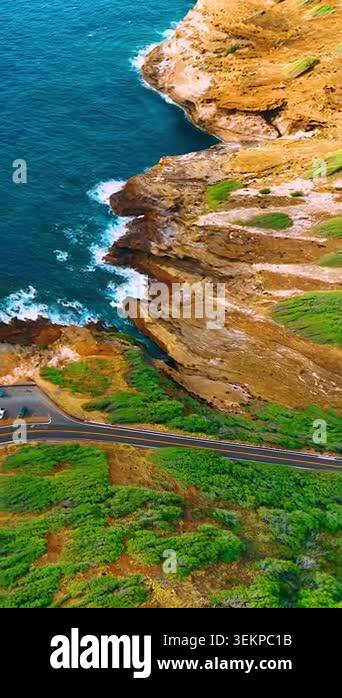 Aerial view of winding coastal road alongside layered volcanic rock ...