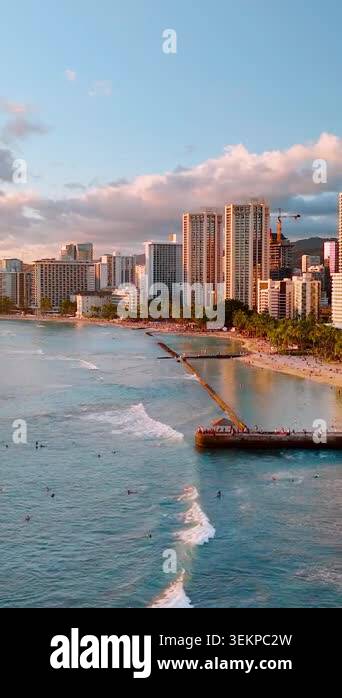 Aerial view of Waikiki beachfront with surfers in water, stone pier ...