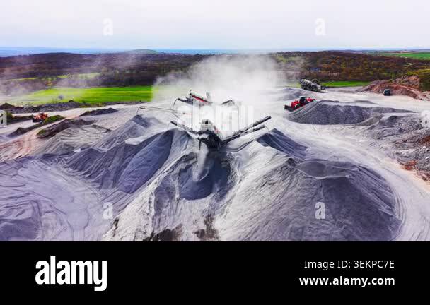 Wide drone perspective of sorting machinery generating dust clouds ...