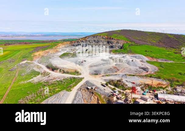Wide drone shot capturing open pit excavation site with distant lake ...