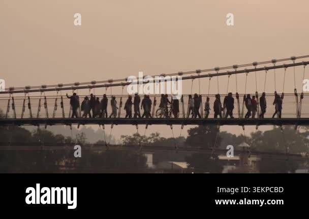 Anonymous crowd of silhouetted people walking on the iconic Ram Jhula ...