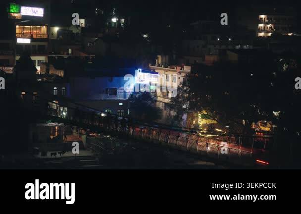 Busy pedestrian traffic crossing the illuminated Laxman Jhula ...