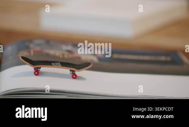 A fingerboard is positioned on an open magazine in this skateboarding ...
