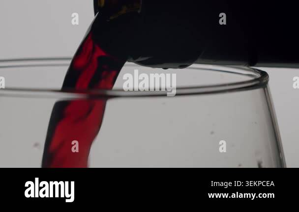 Elegant red wine pouring from the neck of a bottle into a crystal clear ...