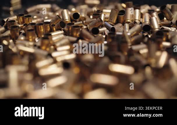 Macro close-up of a large pile of shiny brass spent bullet casings ...