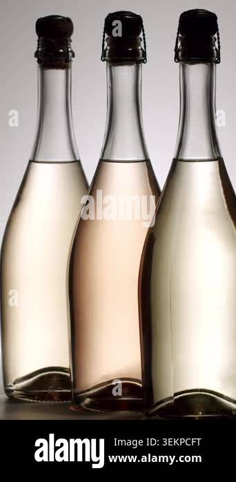 Three elegant bottles of rose and white sparkling wine rotating in slow ...