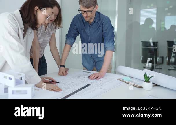 Architecture team analyzing building blueprints and discussing new ...