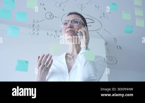 Businesswoman standing in front of a glass board, actively engaging ...