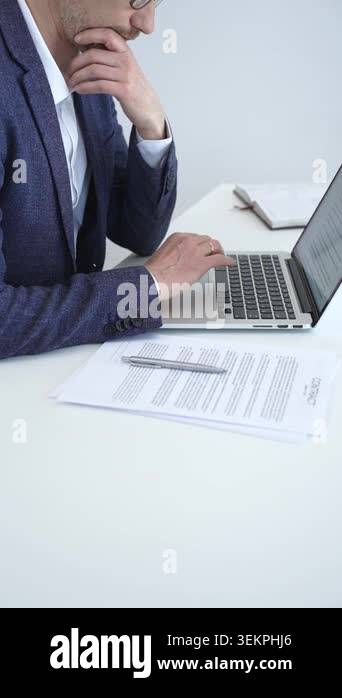Businessman typing on a laptop with his hand resting on his chin ...
