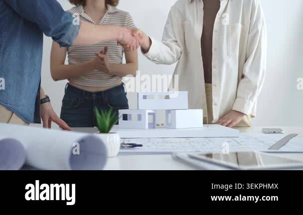 Architects and clients shaking hands, confirming an agreement for a new ...