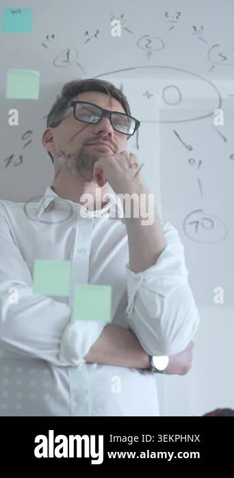 Concentrating businessman in glasses studies hand drawn flowcharts and ...