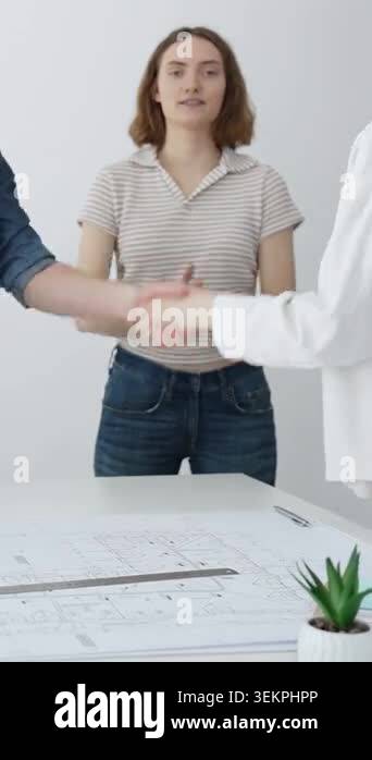 Business people making a deal, shaking hands over architectural project ...