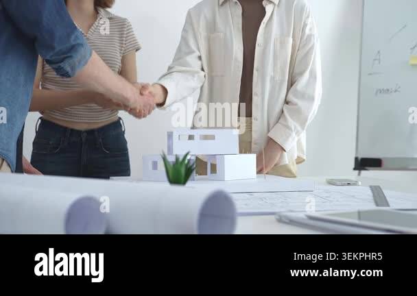Architects and clients shaking hands, confirming an agreement for a new ...