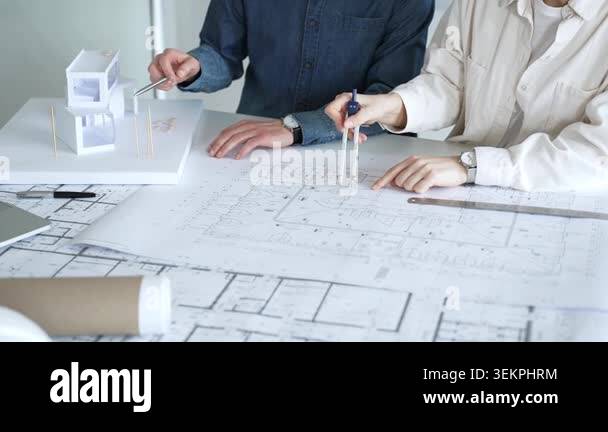 Architects and planners examine detailed blueprints with compass and ...