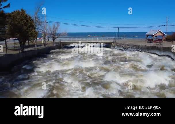 Drone footage of turbulent river rapids rushing beneath a concrete ...