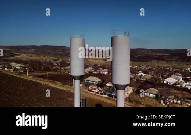 Two tall water towers are visible in a rural area, with houses and ...