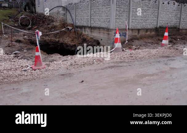 Large sinkhole at a construction site surrounded by traffic cones and ...