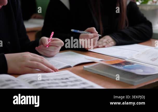 Two young women focus on their studies, writing notes and reading ...