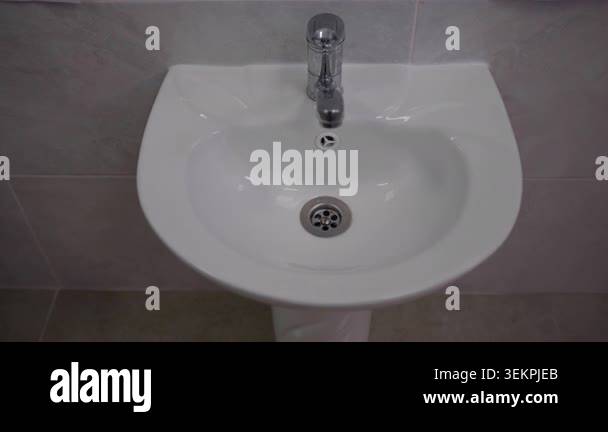 White sink with chrome faucet in a modern bathroom, showcasing the flow ...