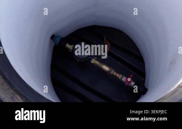 Close-up of a water storage tank reveals a valve, gauge, and piping ...
