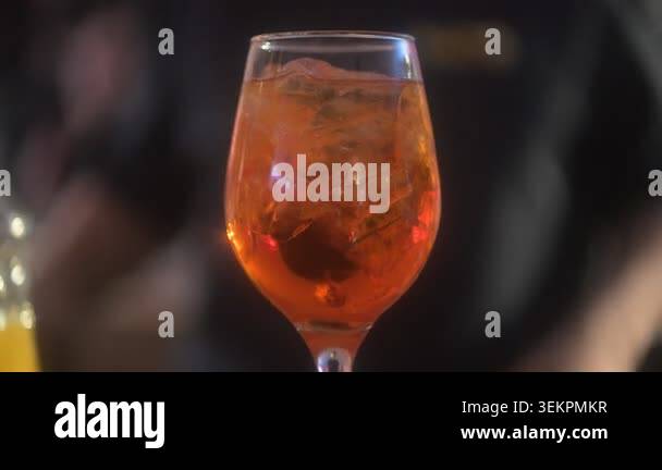 An aperol spritz drink on a glass at a lively bar during the evening ...