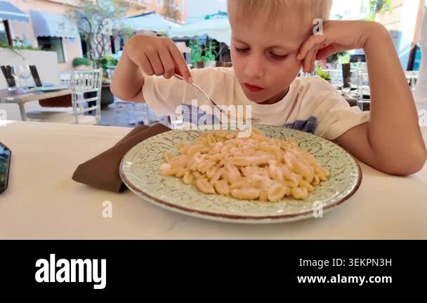 Cute hungry child enjoying a traditional Italian pasta lunch at a local ...
