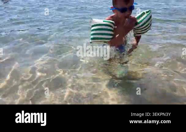 Cute young kid paddling in shallow ocean water near the beach. Concept ...