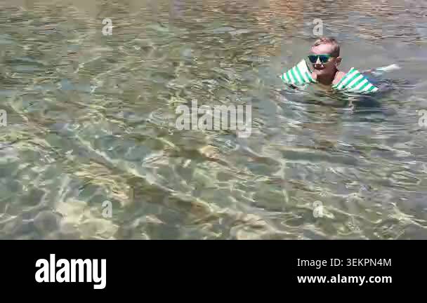 Young child paddling in clear turquoise ocean during a sunny day at a ...