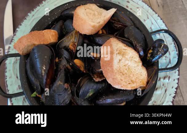 Close-up of hot steaming mussels with croutons at a restaurant table ...