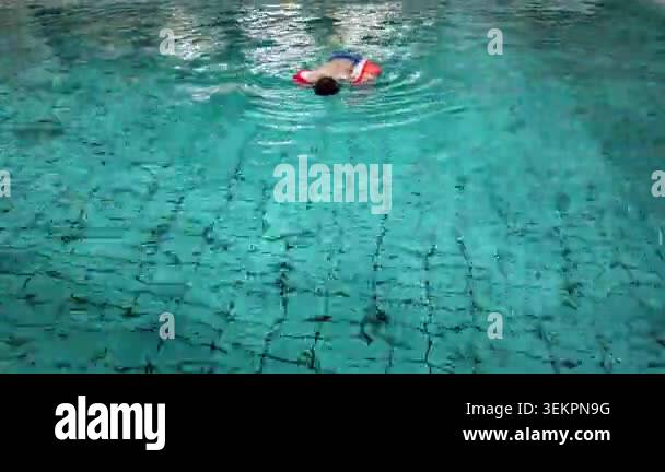 High angle shot of a child swimming laps in a clear turquoise water of ...