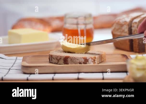 Soft butter spreading with a knife on a slice of fresh bread on wooden ...