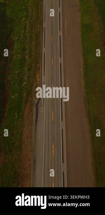 Vertical Screen: Aerial drone footage of a straight two-lane highway ...