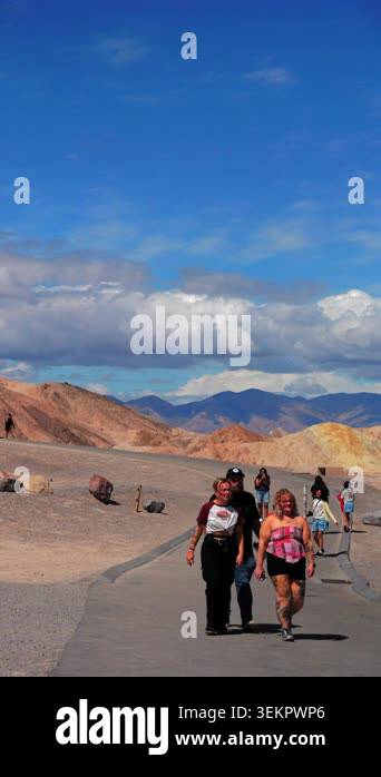 Vertical Screen: Tourists walk along paved pathway at Zabriskie Point ...