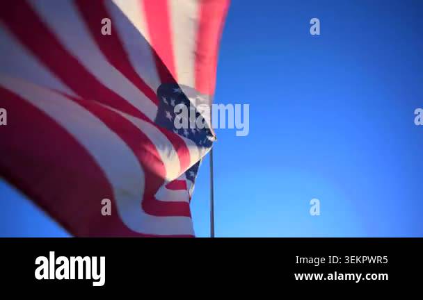 USA flag waves majestically against a vibrant clear blue sky. The ...