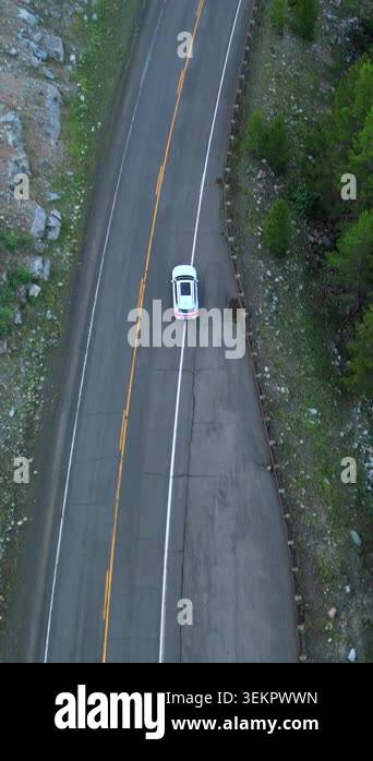 Vertical Screen: Drone aerial footage captures white car traveling ...