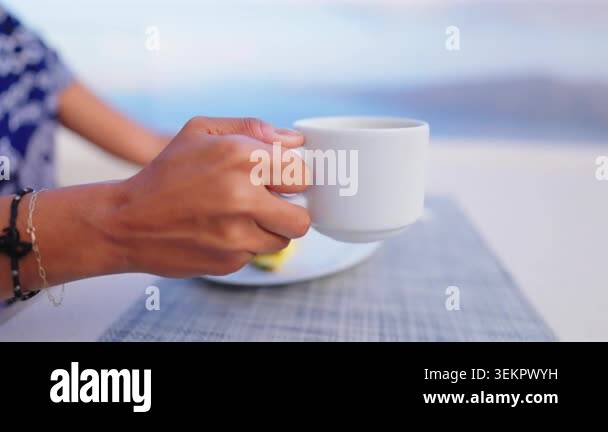 Woman wearing blue sunglasses and embroidered dress sips coffee from ...
