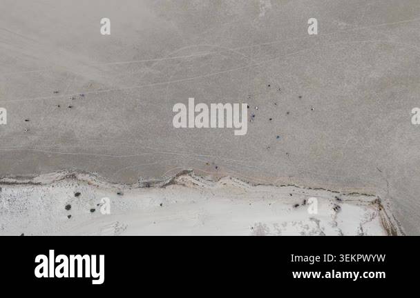 Aerial view of a wide empty beach with cliffs, calm sea, and small ...