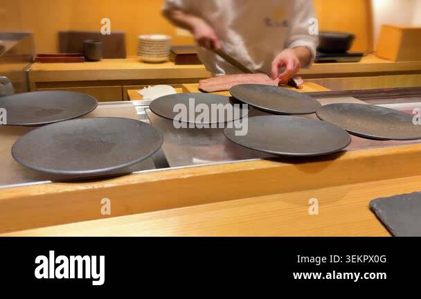 Professional Japanese sushi master slicing fresh raw tuna fish fillet ...