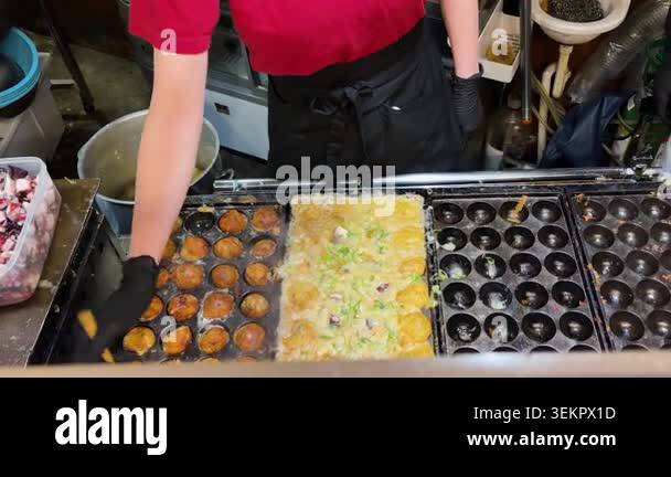 Street food vendor cooking traditional Japanese takoyaki octopus balls ...